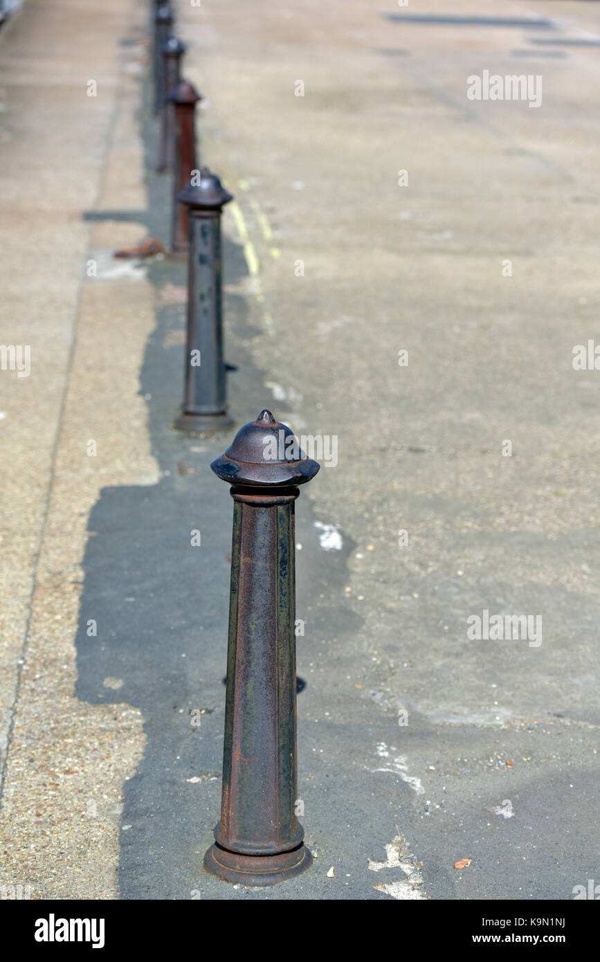 some cast iron bollards in a row on the edge of a pathway, pavement or ...