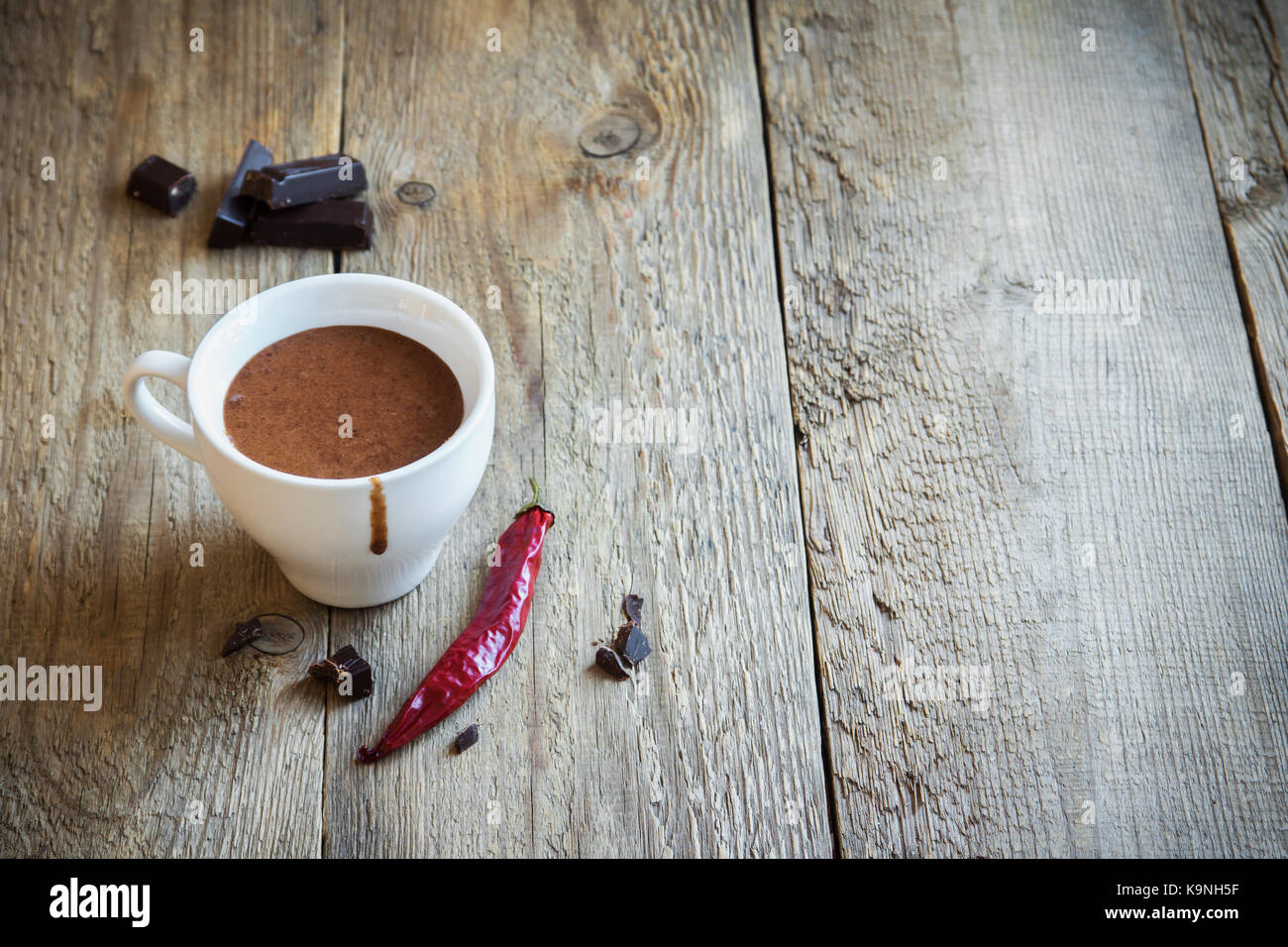 Hot Chocolate with chili pepper and chocolate pieces over rustic wooden ...