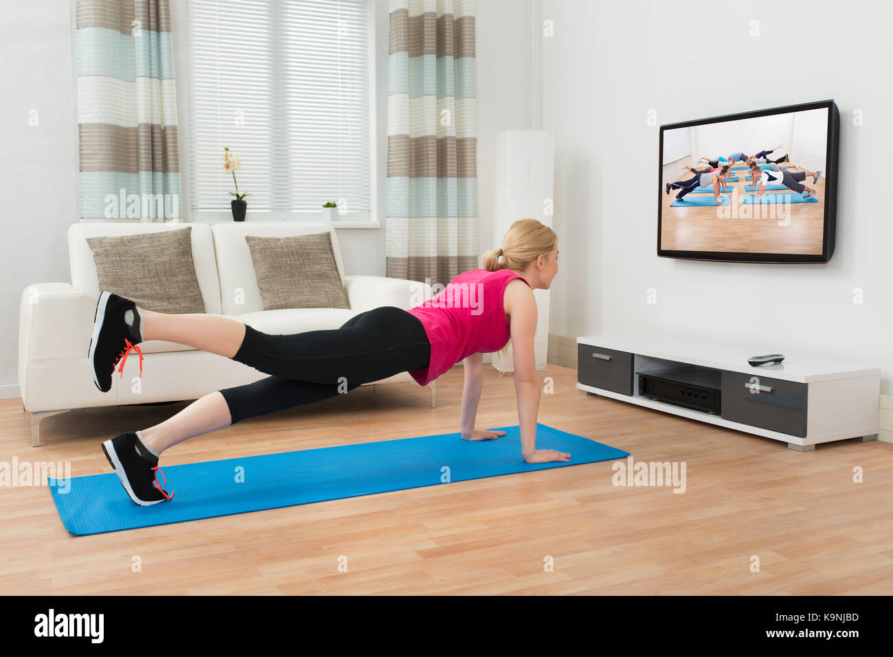 Young Woman Doing Workout While Watching Television In House Stock ...