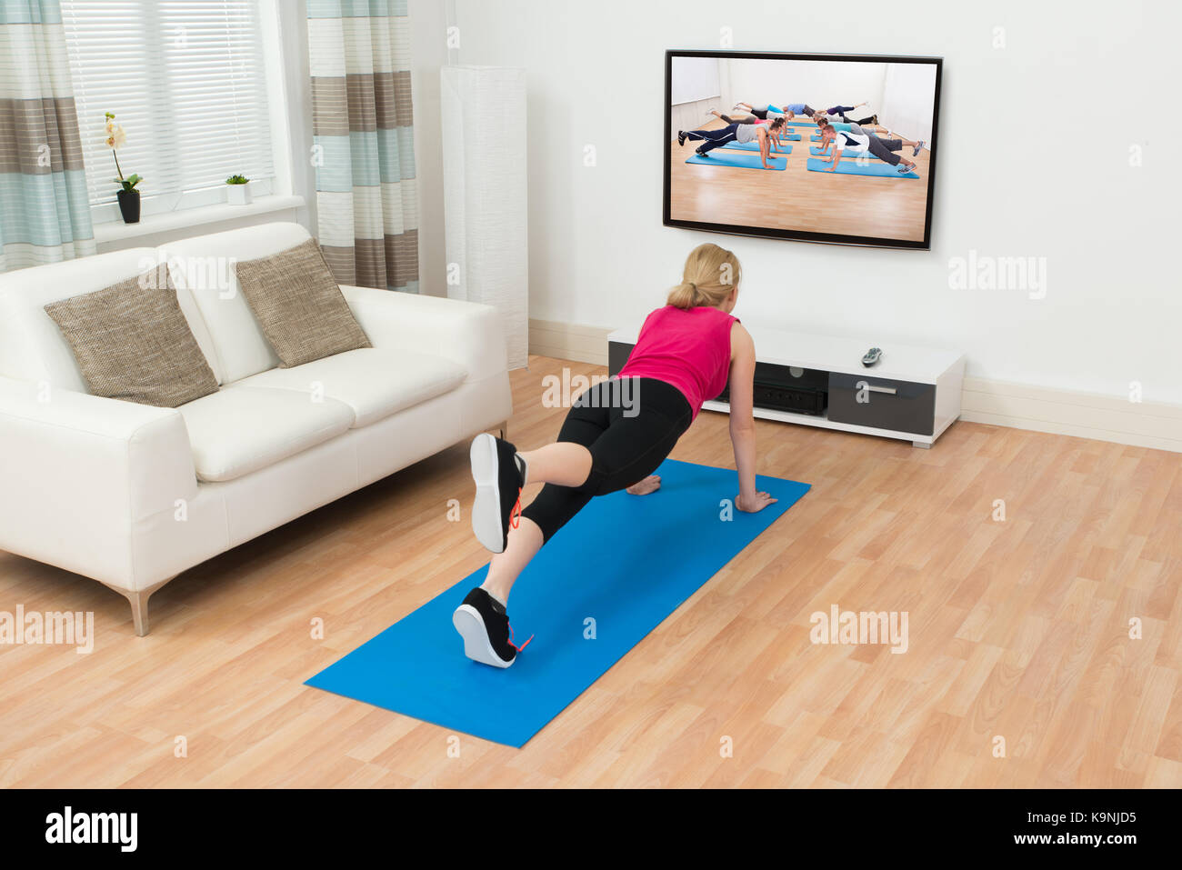 Young Woman Doing Workout While Watching Television In House Stock ...