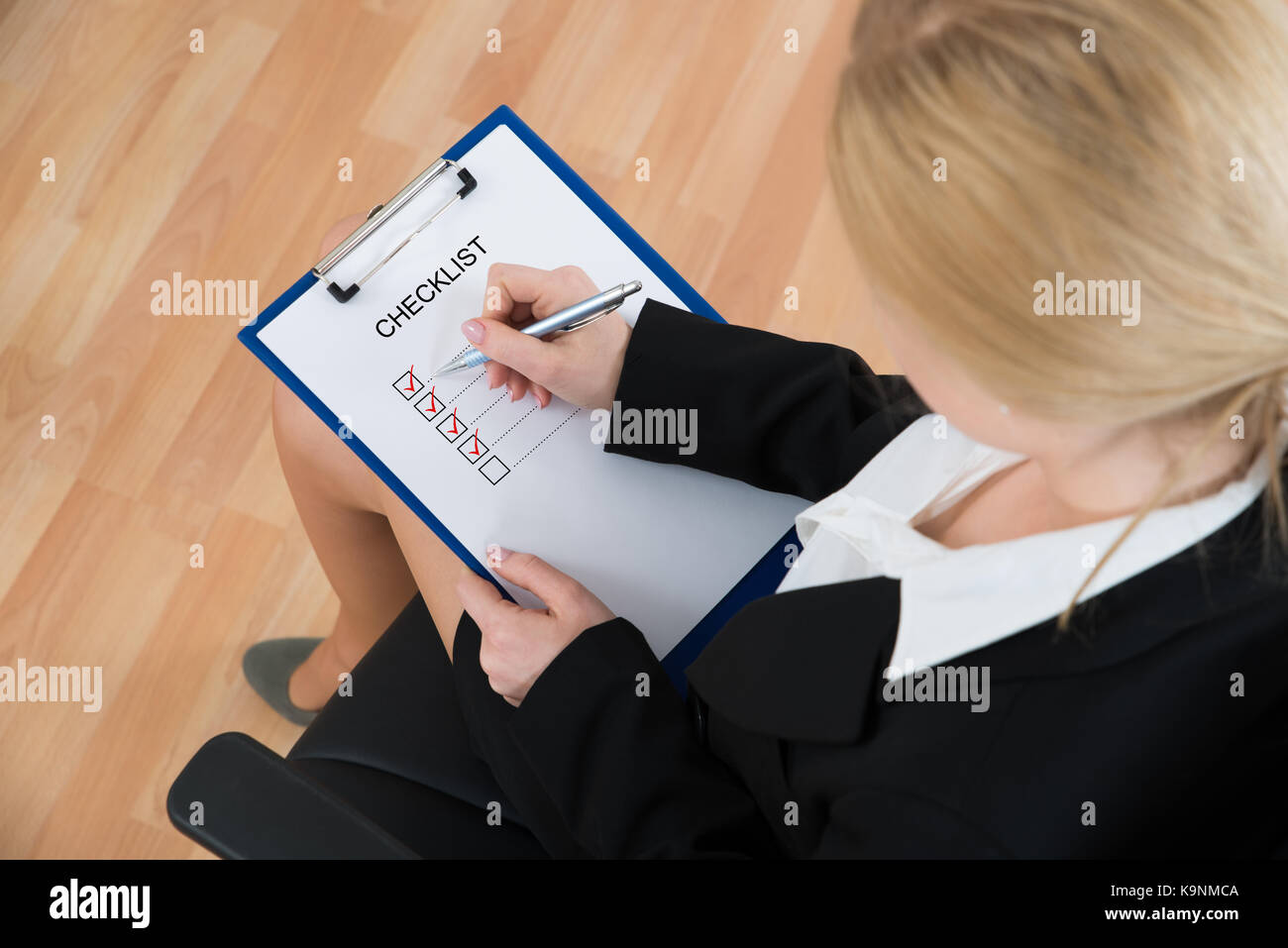 Businesswoman Marking Checklist With Pen On Clipboard At Workplace ...