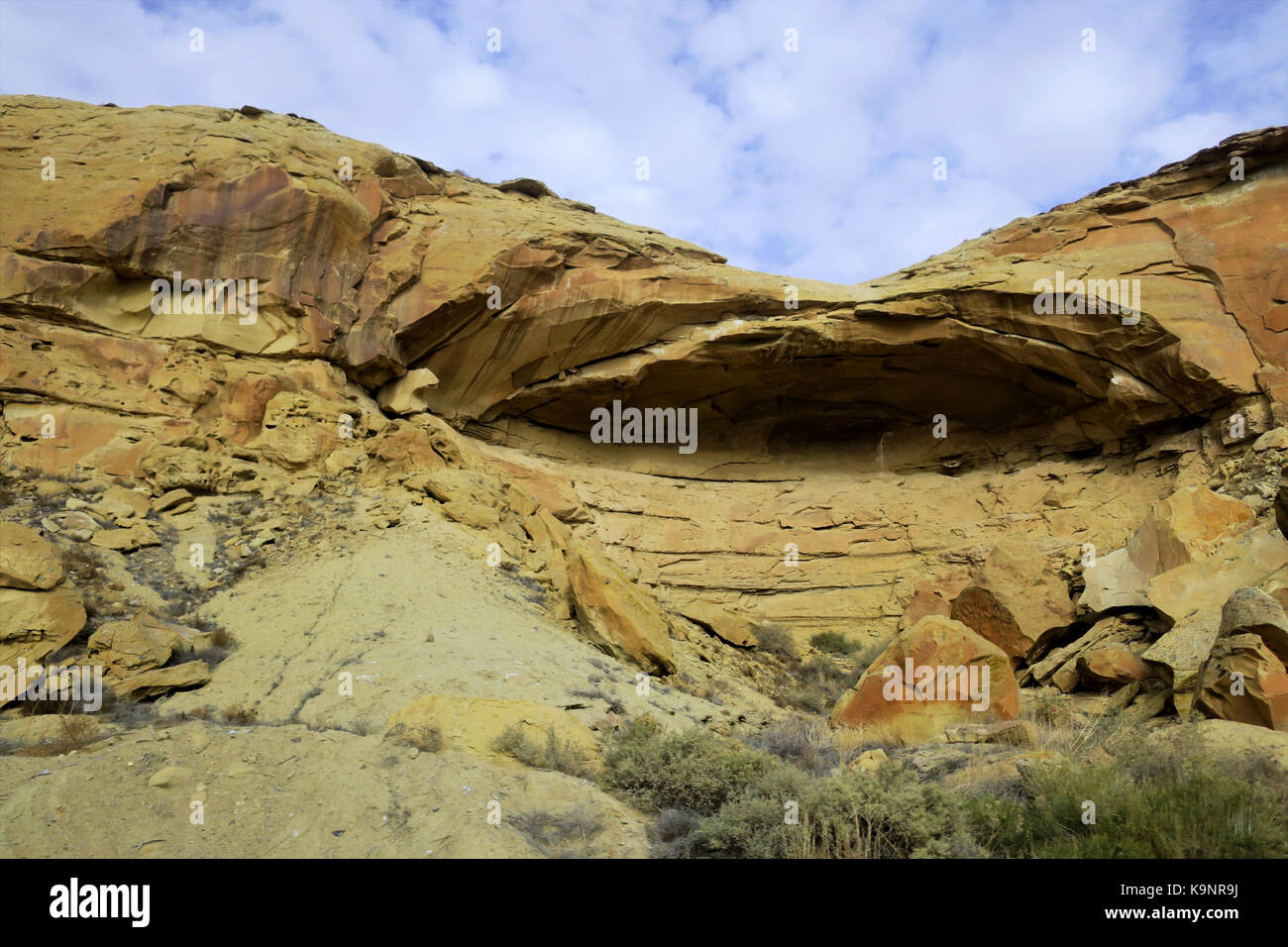A beautiful natural carved and curved rock wall with fluffy clouds ...