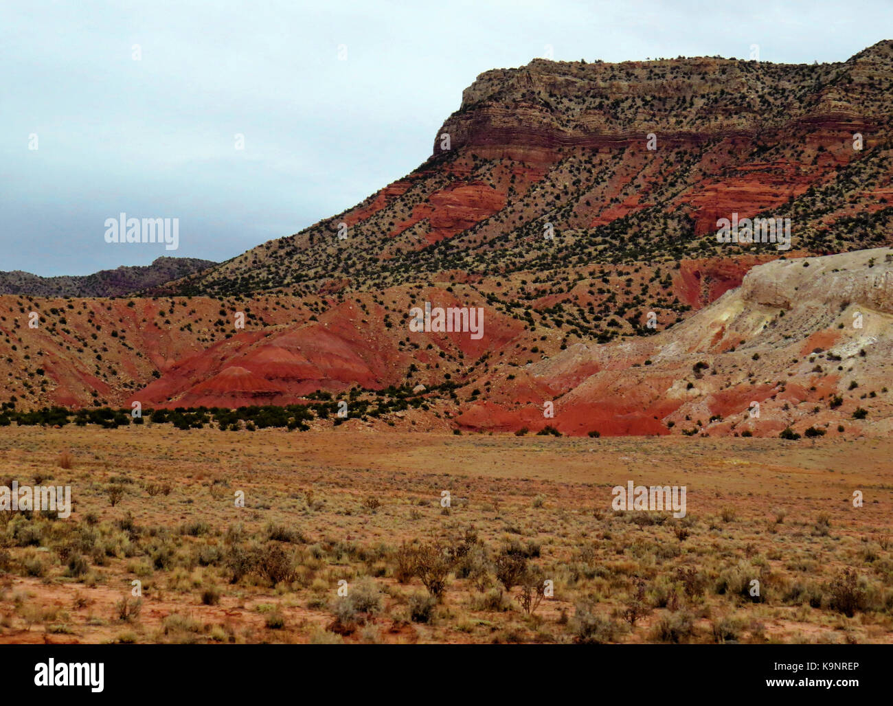 A red layered rock formation with a bright blue sky Stock Photo - Alamy