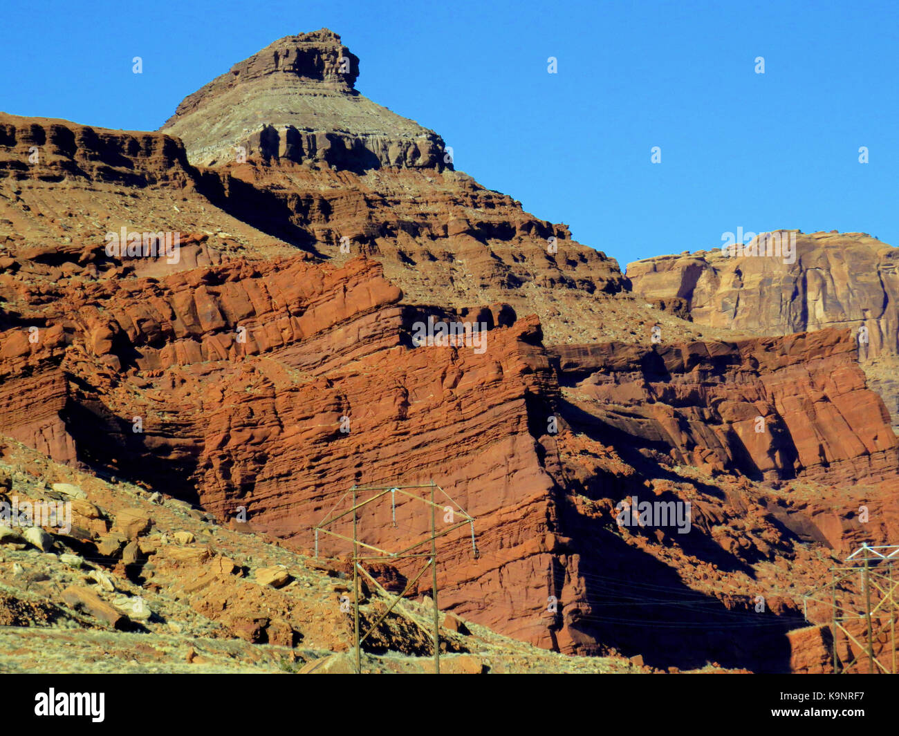 A red layered rock formation with a bright blue sky Stock Photo - Alamy