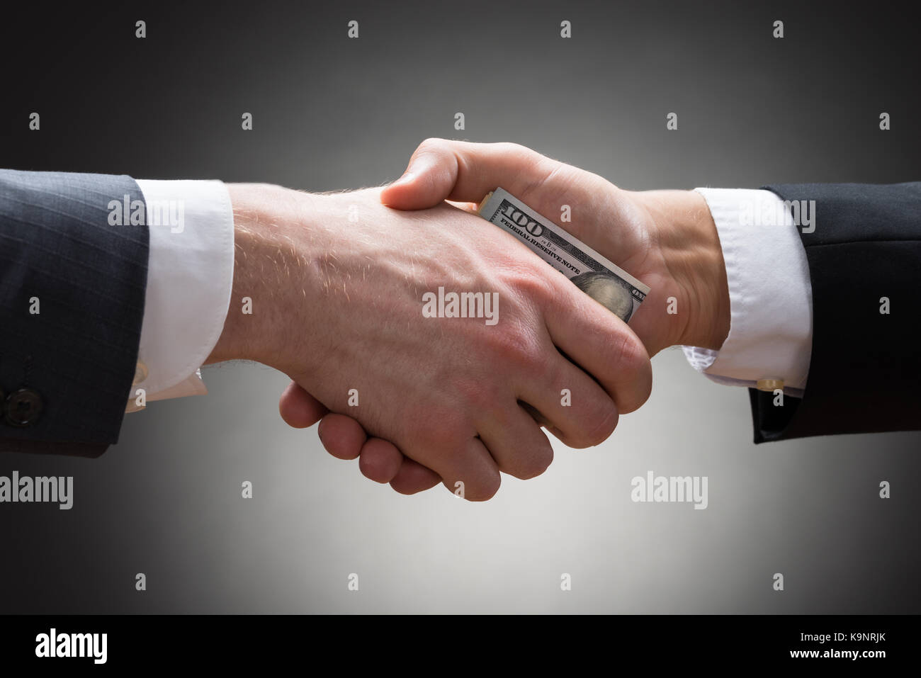 Close-up Of Two Businesspeople Shaking Hands With Money Stock Photo - Alamy