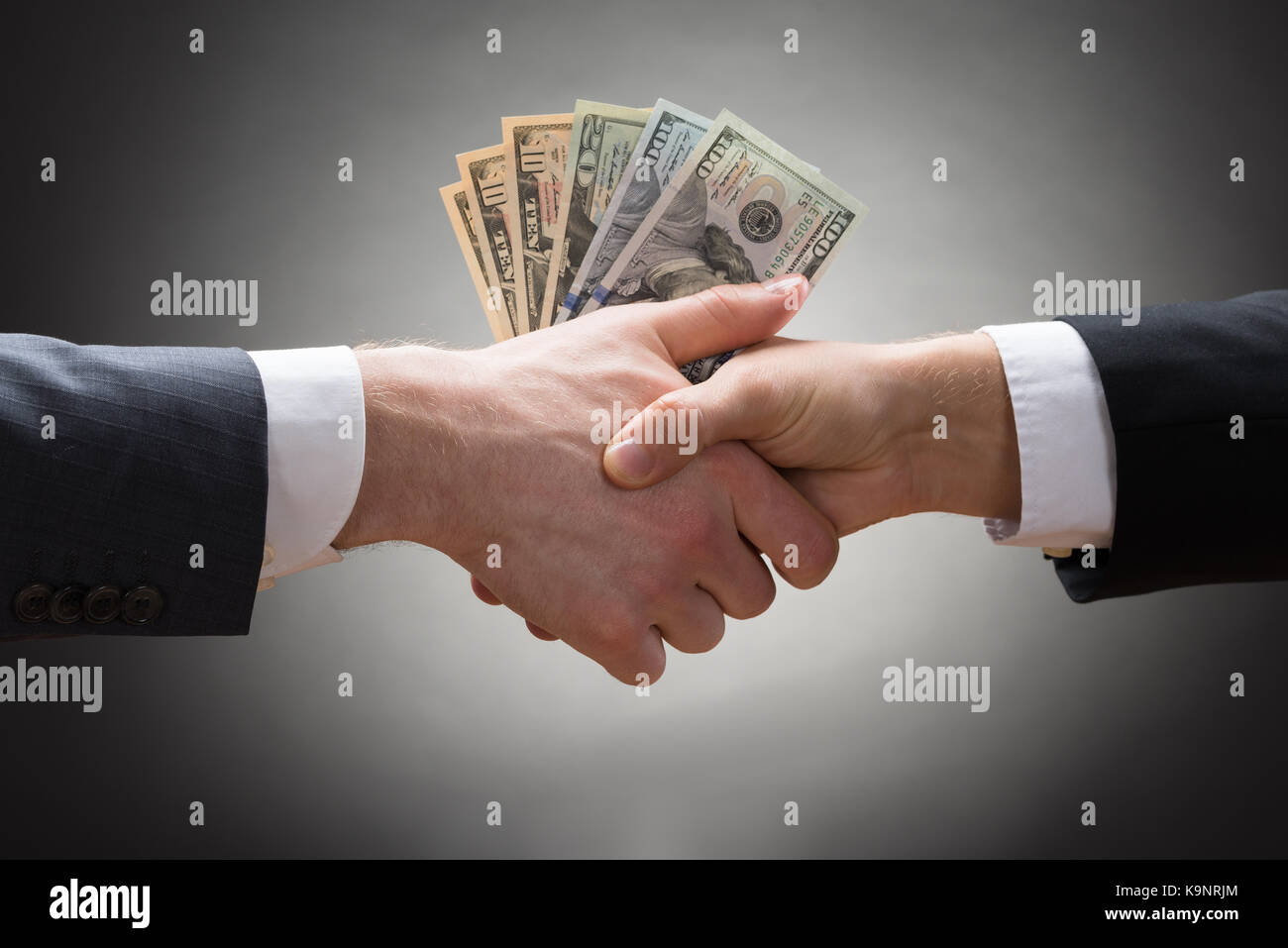 Close-up Of Two Businesspeople Shaking Hands With Money Stock Photo - Alamy