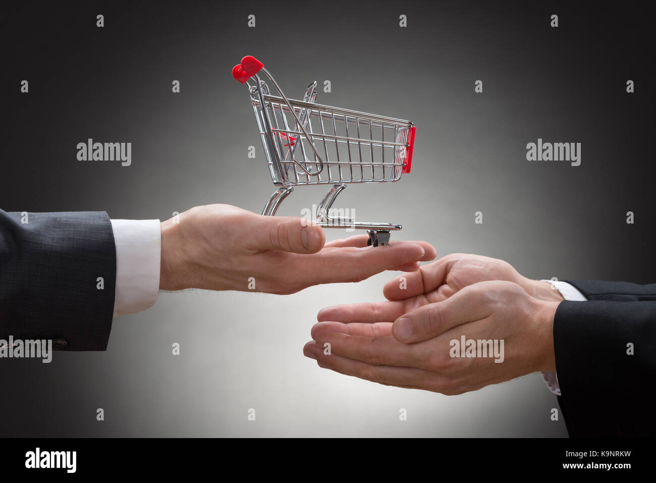Close-up Of Businessman Hand Giving Mini Shopping Cart To Other ...