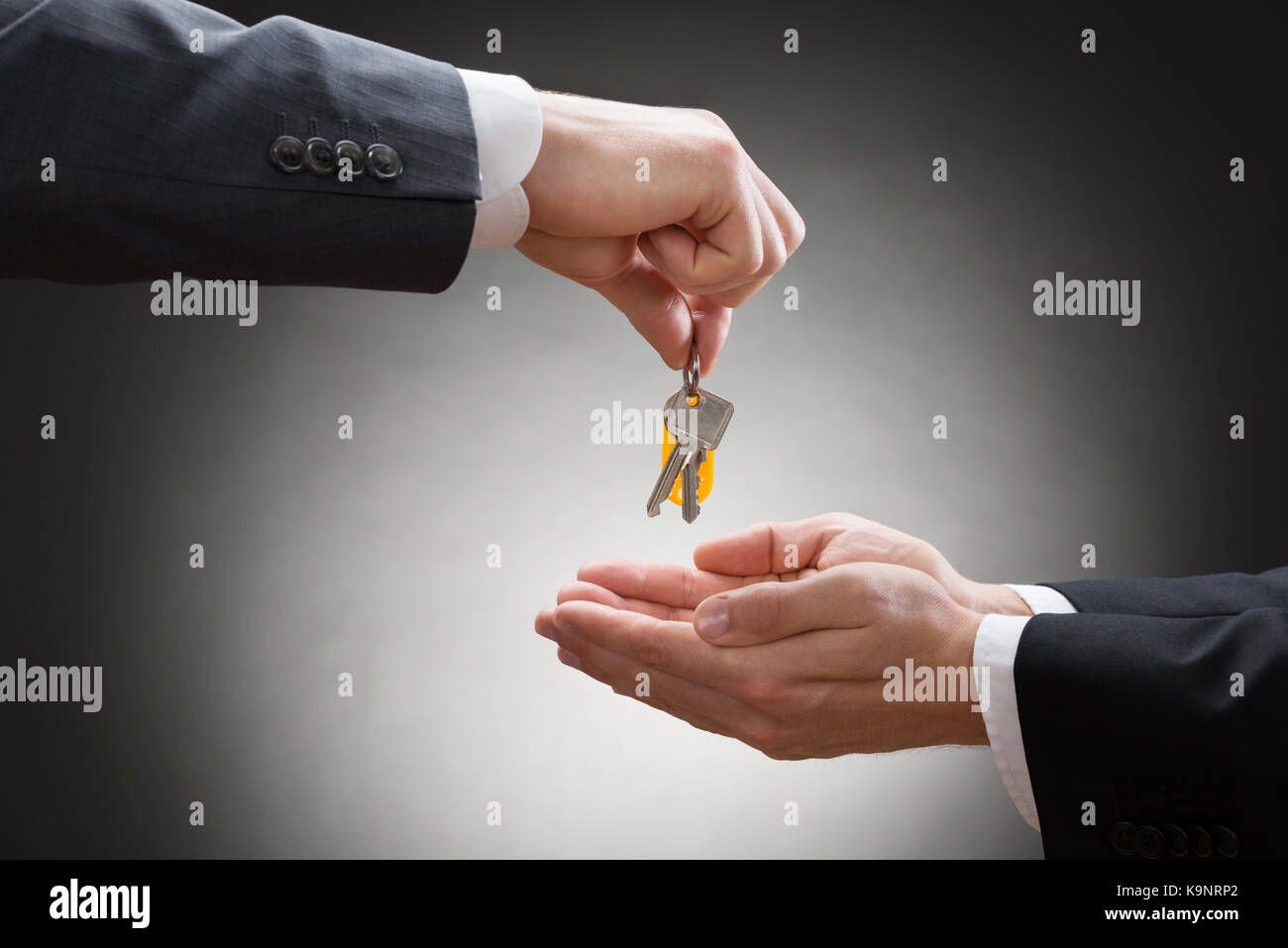 Close-up Of A Businessman's Hand Handing House Key To Another Person ...