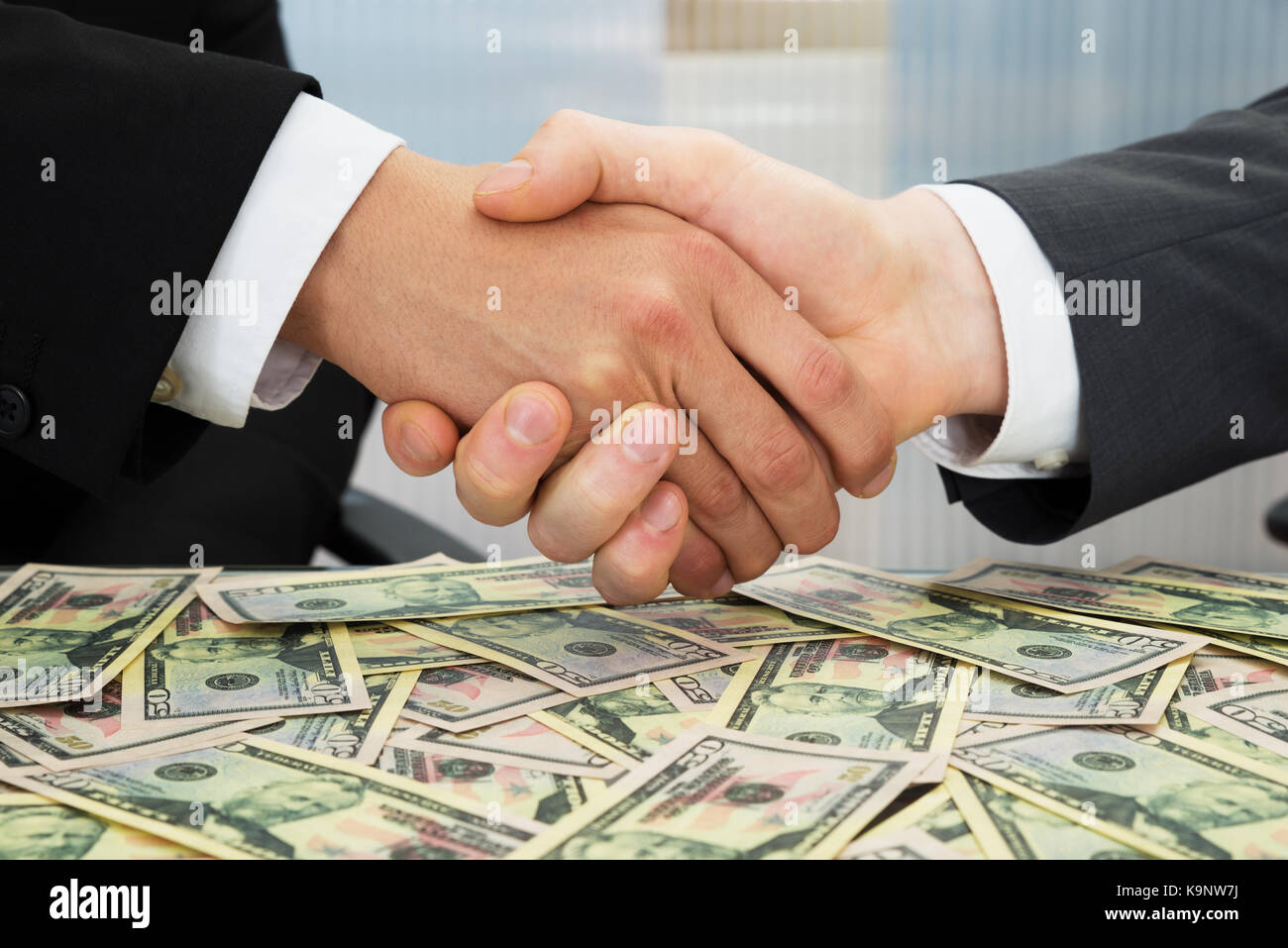 Close-up Of Businesspeople Shaking Hand Over Heap Of Banknotes Stock ...