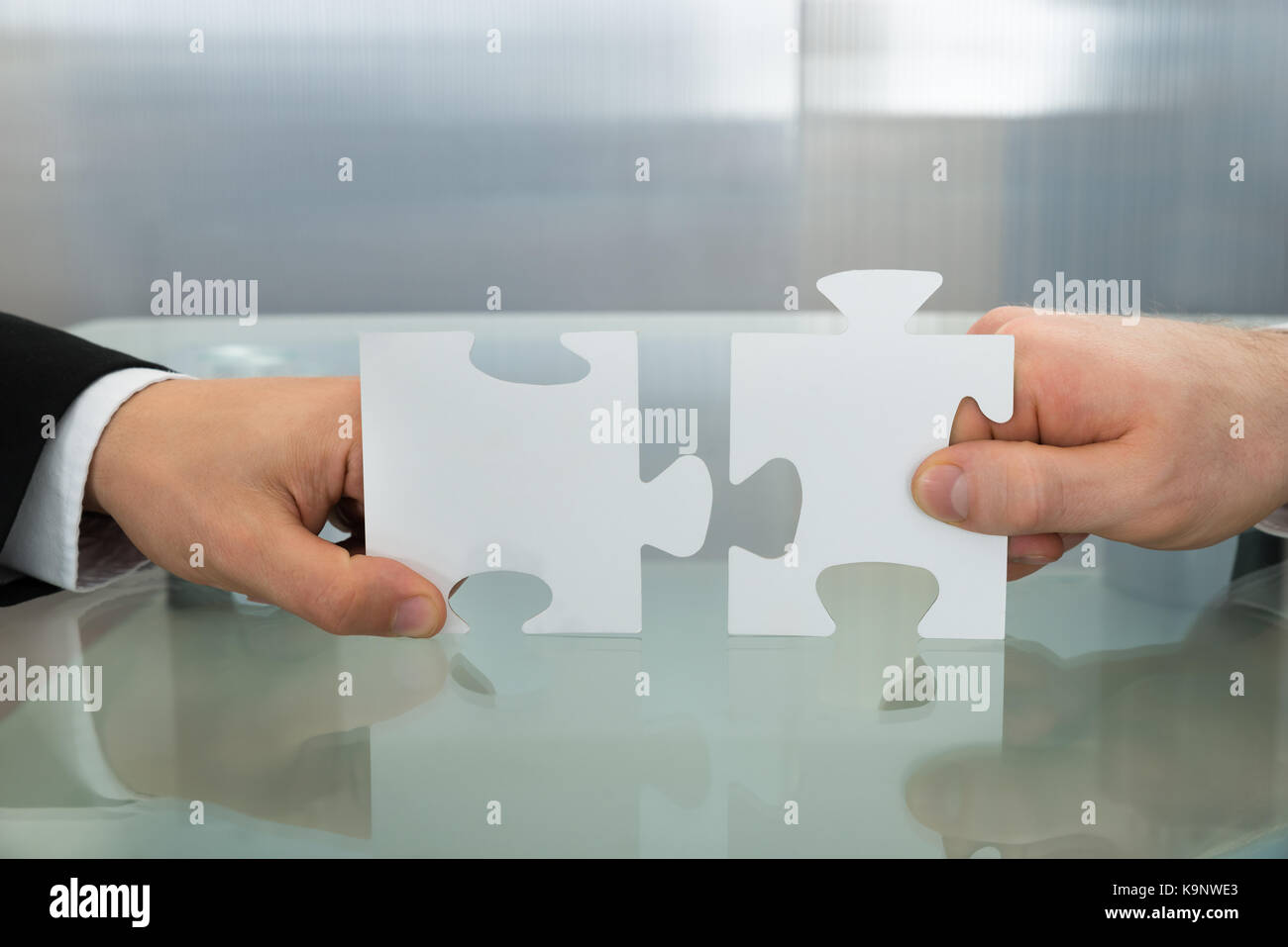 Close-up Of Two Businessman Hands Holding Jigsaw Puzzle On Office Desk ...