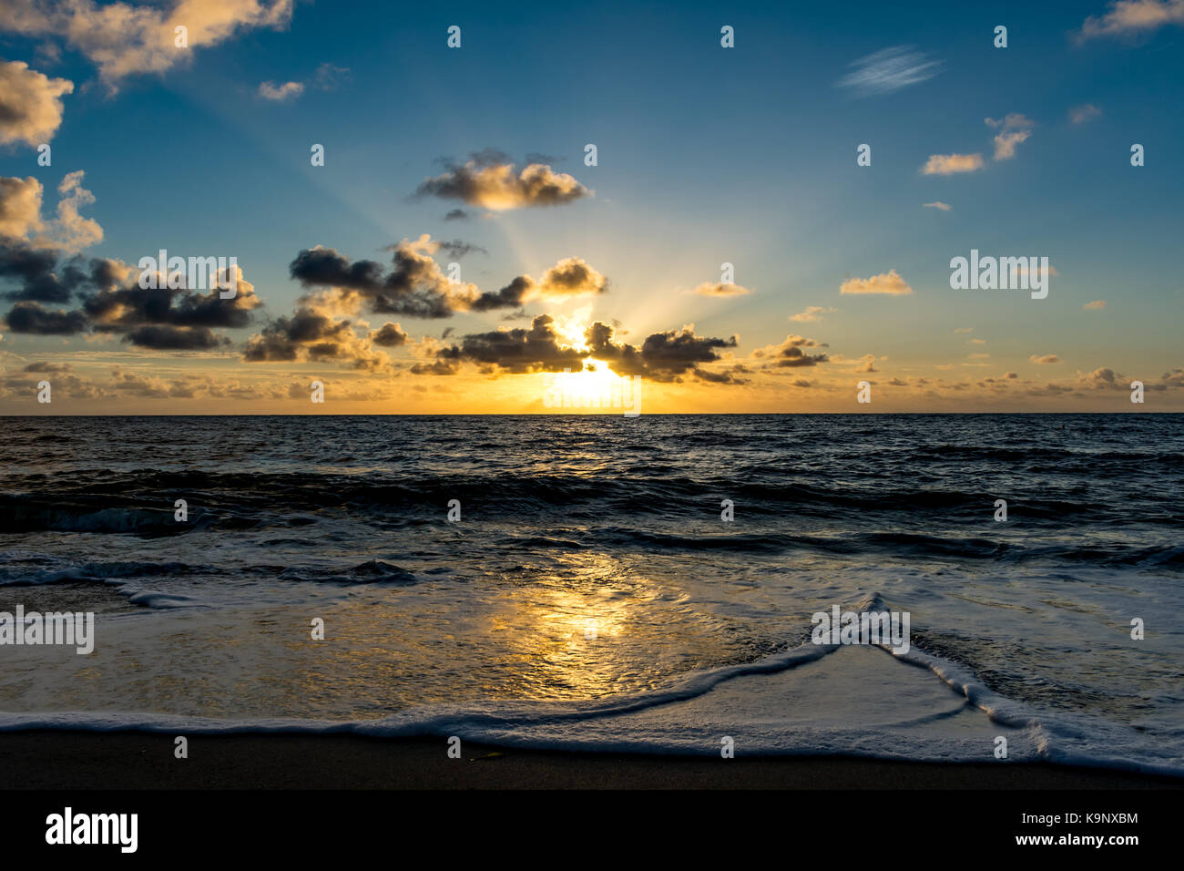 yellow sun with light rays and blue sky at the beach on a summer ...