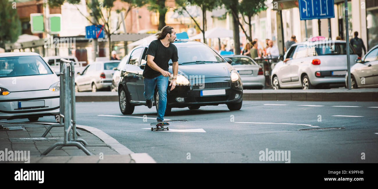 Professional skater riding skate on the main streets through cars and ...