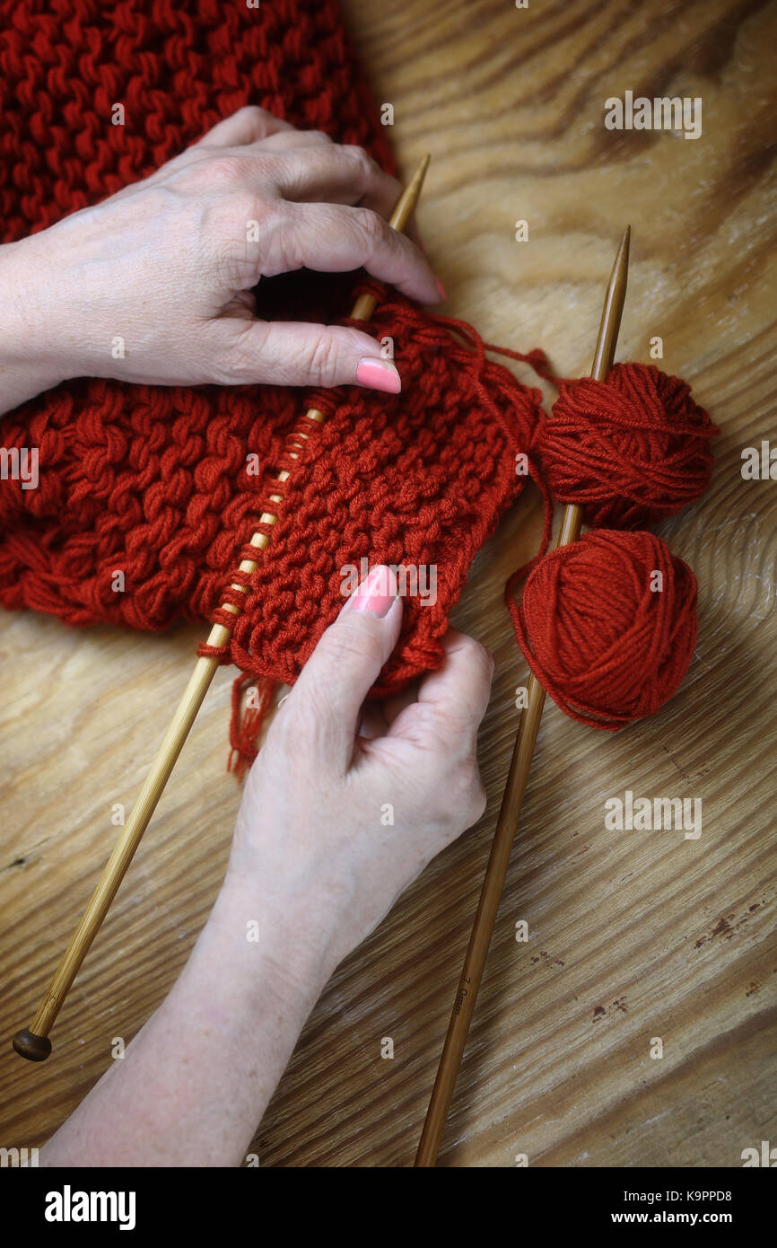 elderly woman is engaged in knitting warm sweaters for her grand Stock ...