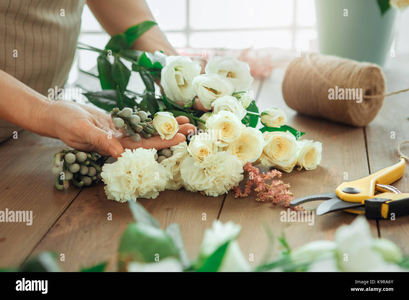 Young female florist working with flowers making bouquet Stock Photo ...
