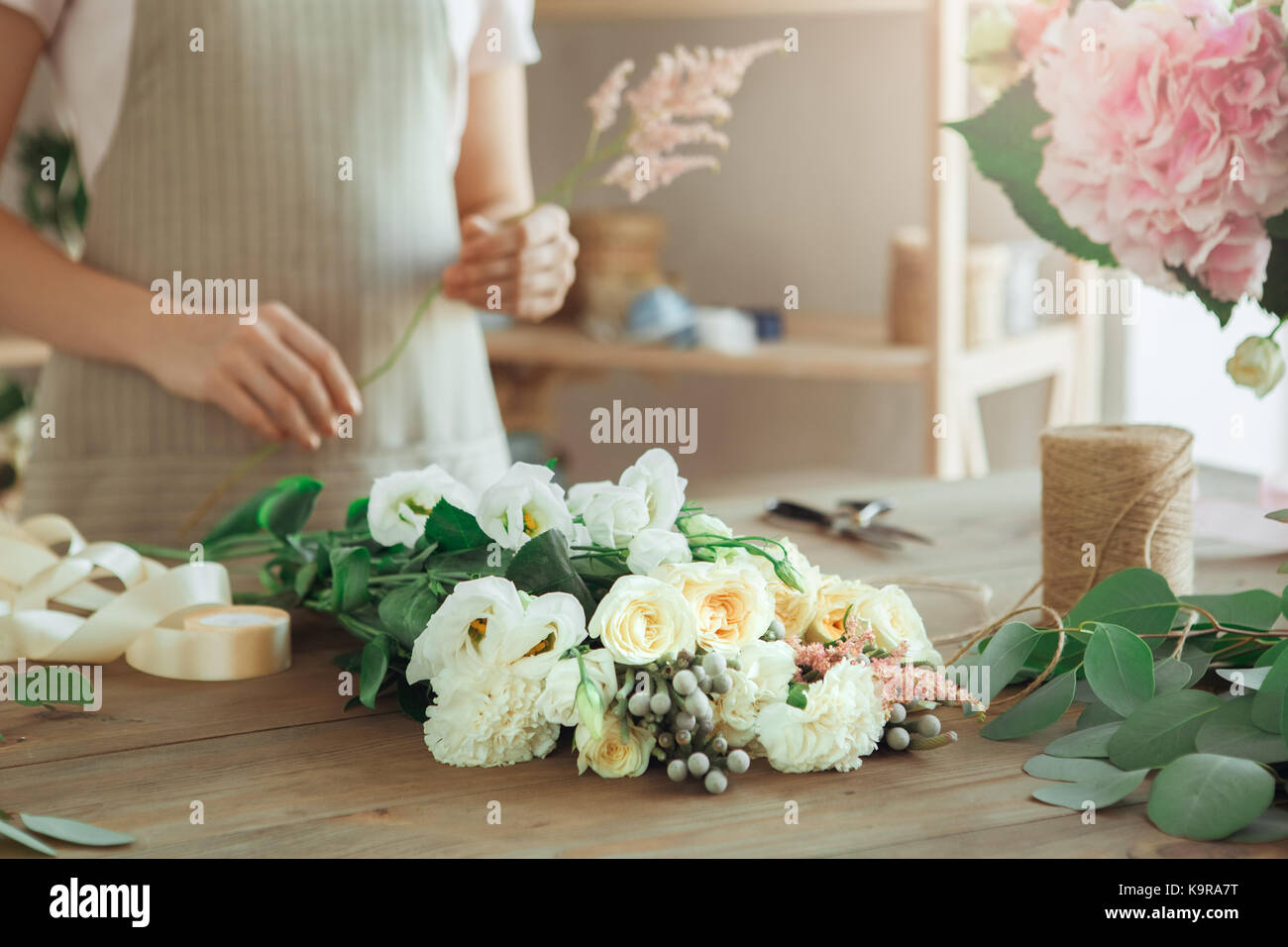 Young female florist working with flowers making bouquet Stock Photo ...