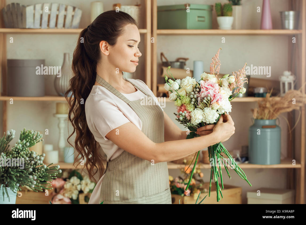Young female florist working with flowers making bouquet Stock Photo ...