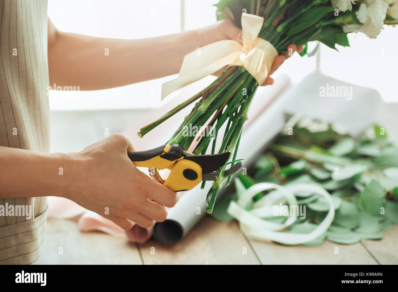 Young female florist working with flowers making bouquet Stock Photo ...