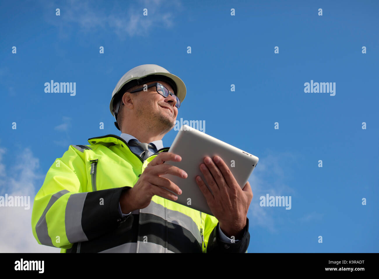 Construction engineer wearing safety vest against blue sky Stock Photo ...