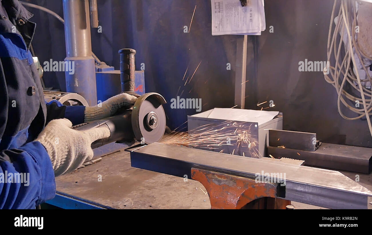 Craftsman sawing metal with disk grinder in workshop. Metal sawing ...