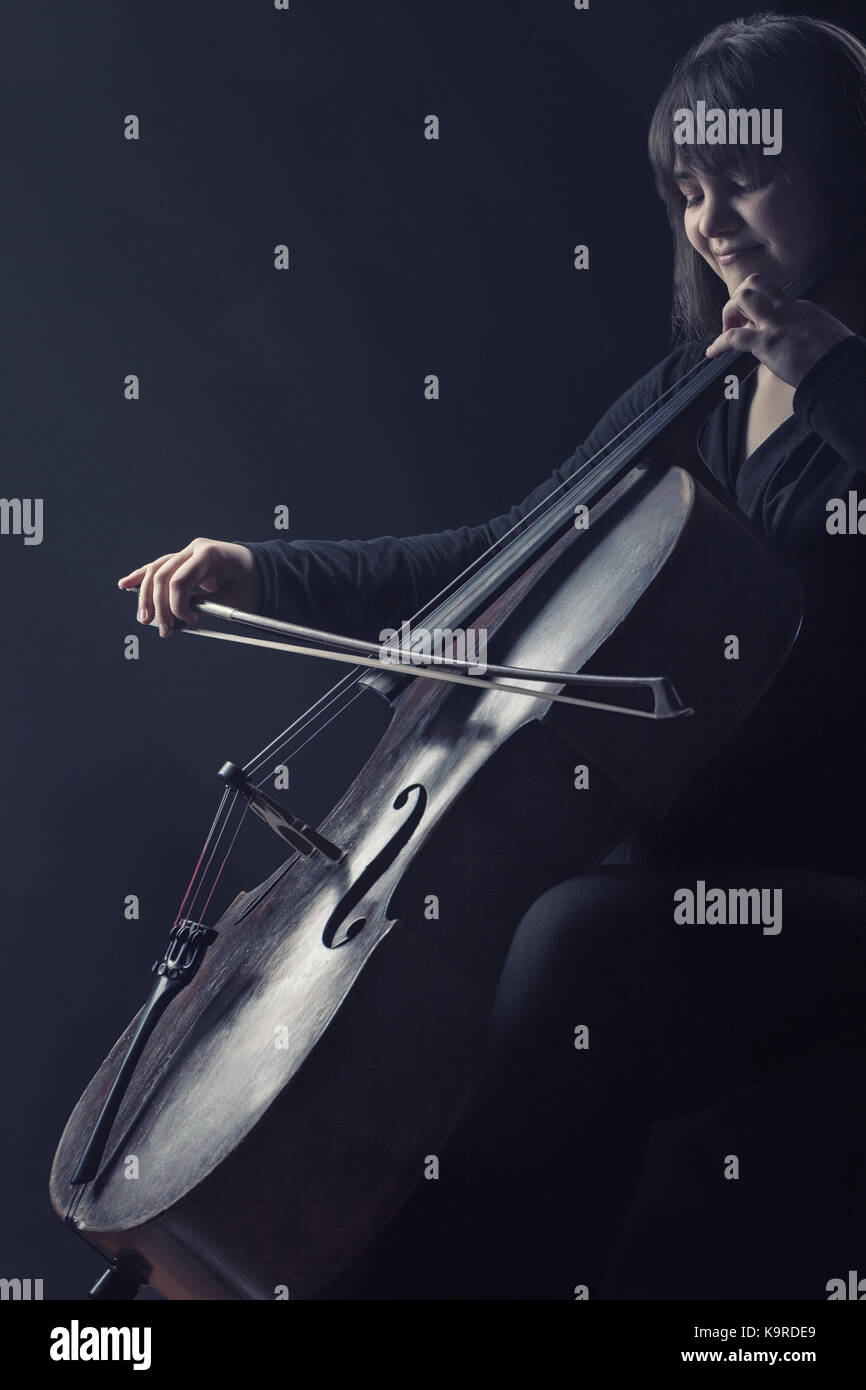 Close-up of cellist playing classical music on cello against a black ...