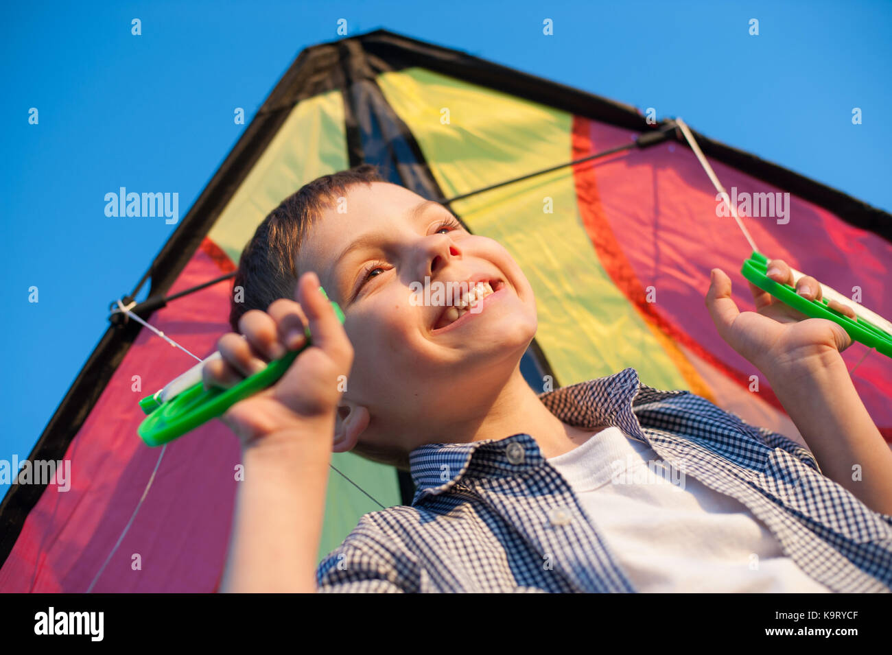 smiling little boy with colorful kite behind his shoulders with blue ...