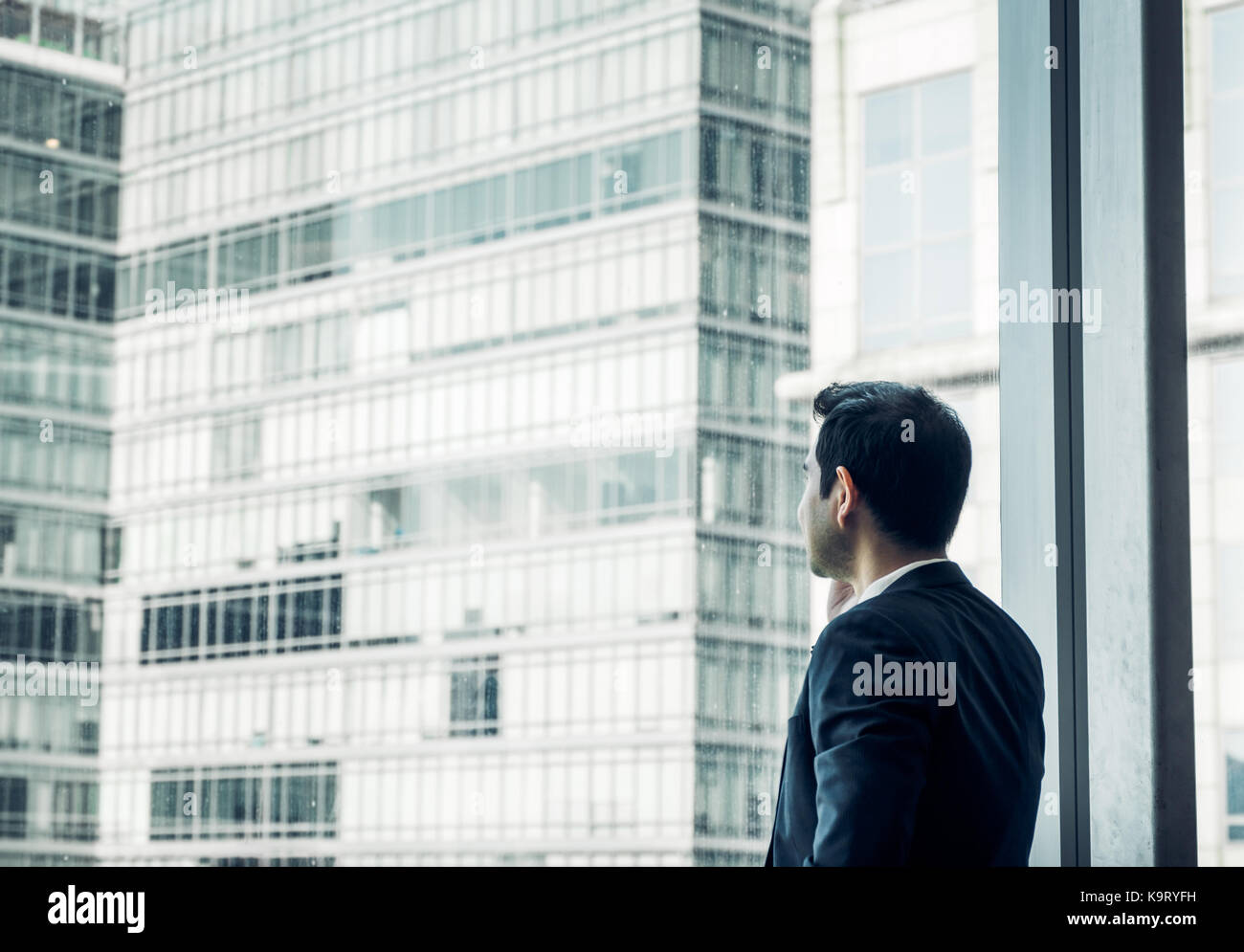 Businessman using mobile phone near office window at office building ...