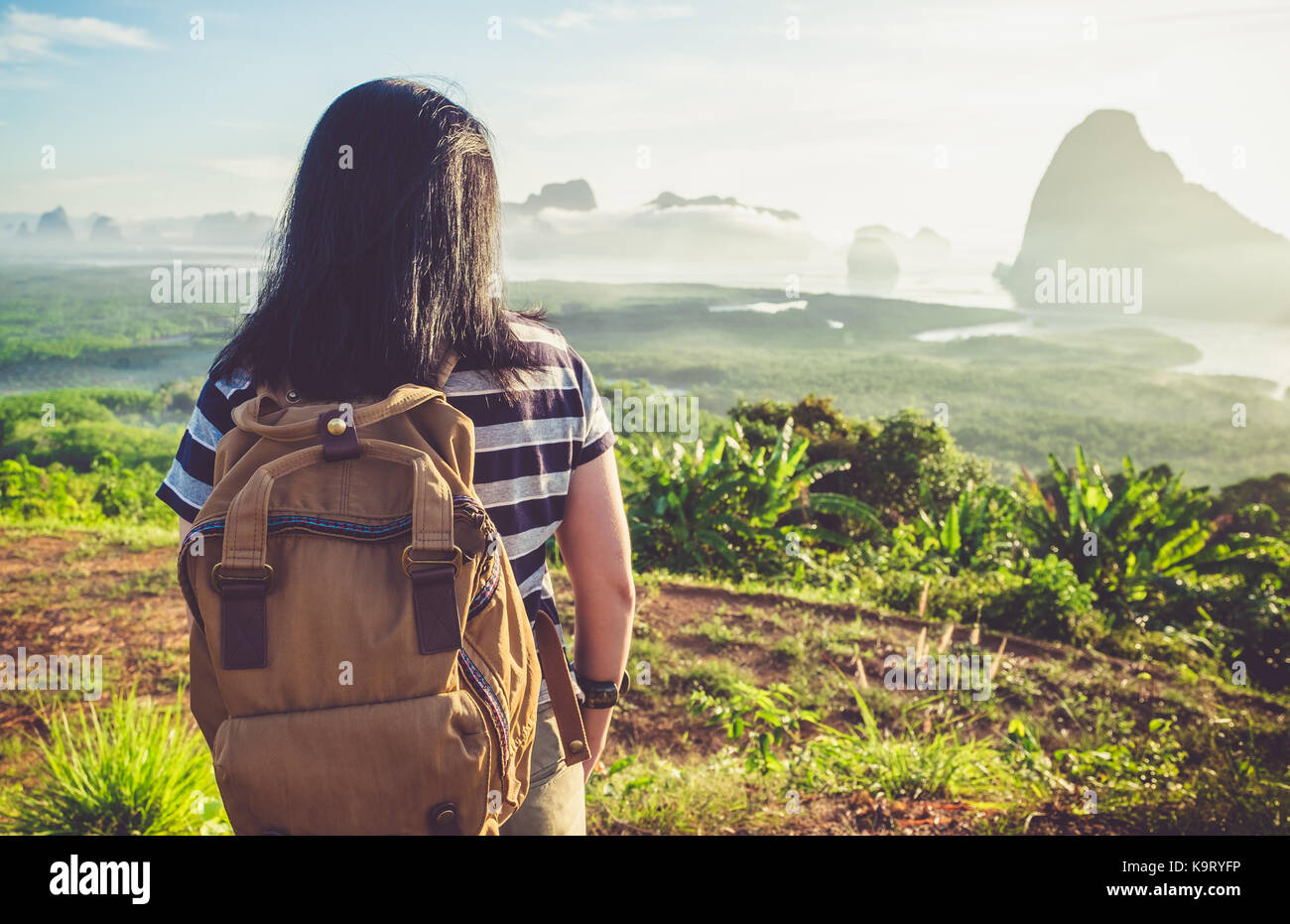 Happy young traveler woman backpacker looking backward to camera with a ...