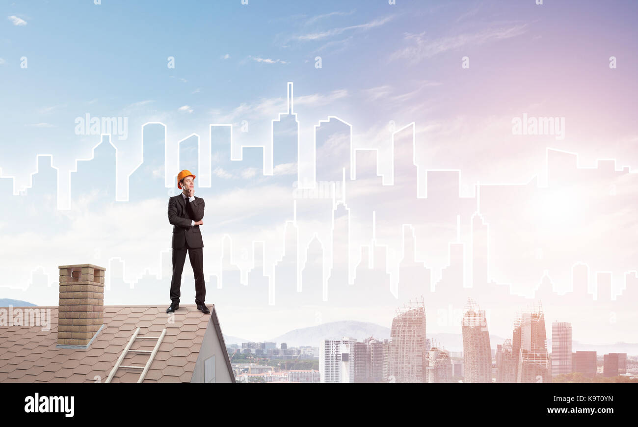 Engineer man standing on roof and looking away. Mixed media Stock Photo ...