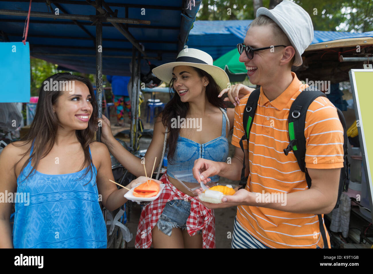 Cheerful Group Of Friends Eat Fresh Fruits Exploring Asian City And ...