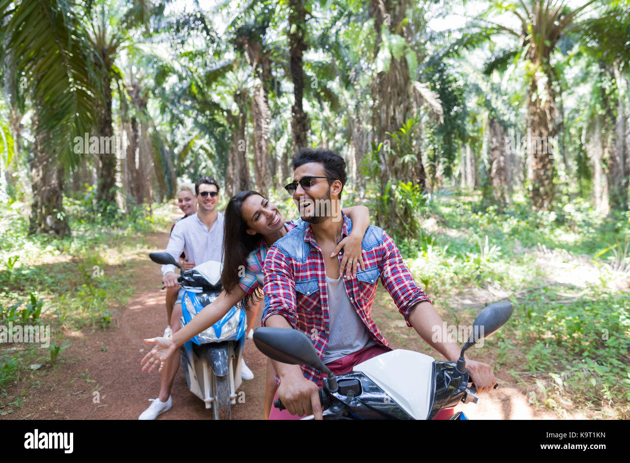 Two Young Couples Driving Scooter Bike In Tropical Forest Young Group ...
