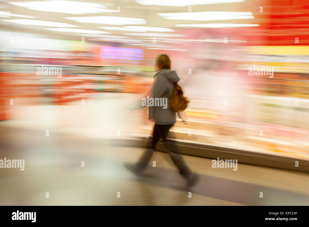 Woman walking against shop window Stock Photo - Alamy