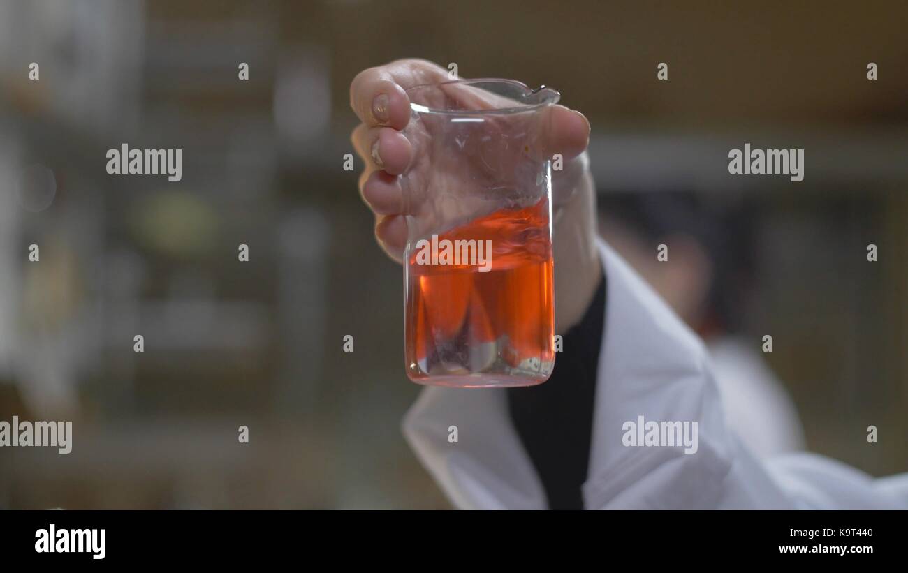 Chemist hands mixed substance of red color in test tubes. Doctor Pours ...