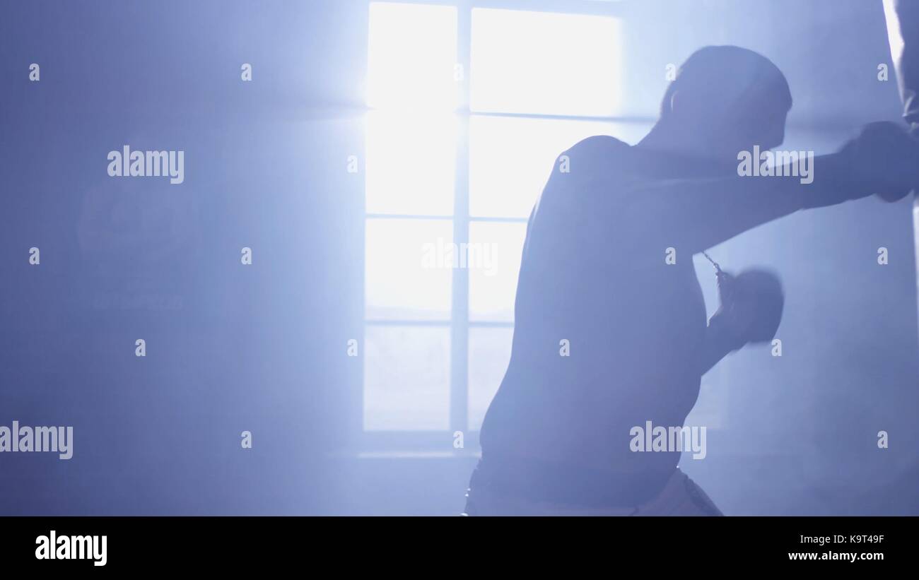 Muscular handsome fighter giving a forceful forward kick during a ...