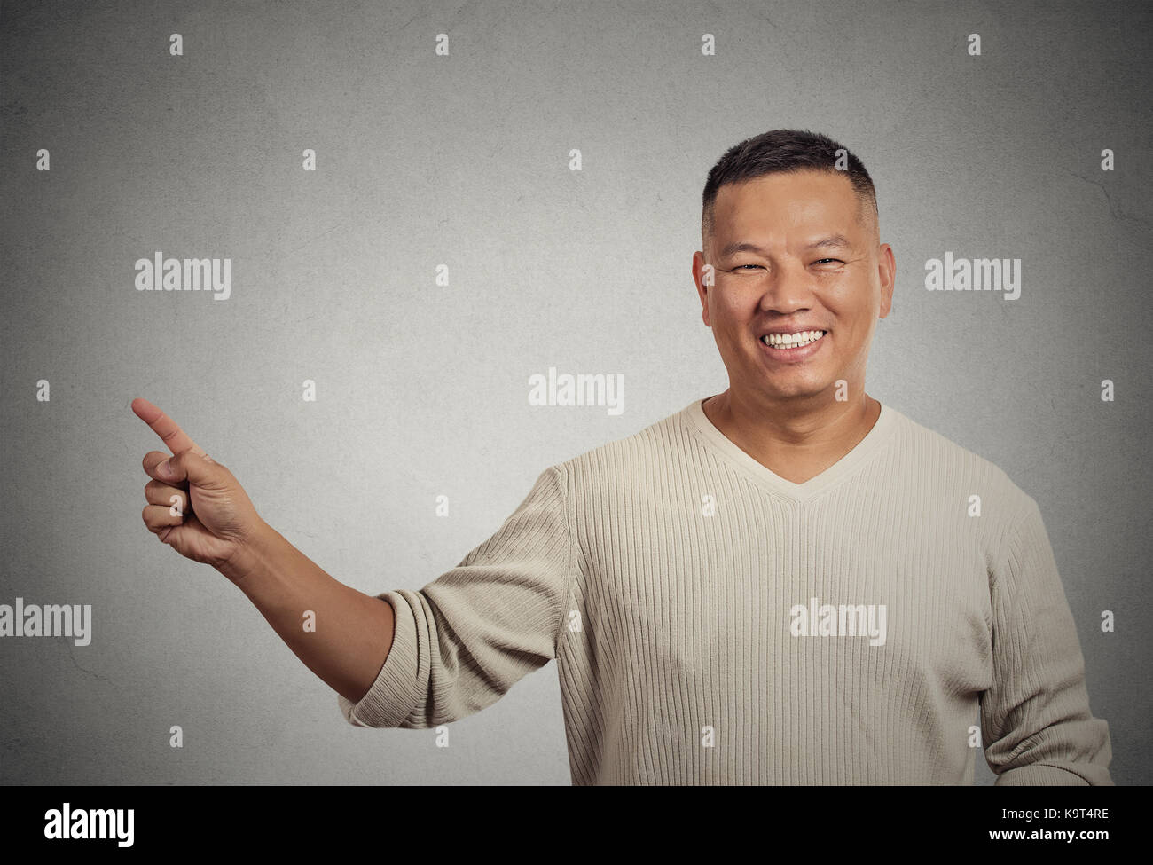 Handsome welcoming man smiling pointing with finger presenting copy ...