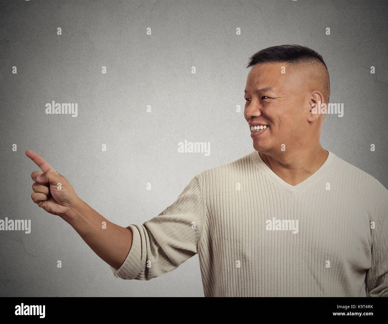 Handsome welcoming man smiling pointing with finger presenting copy ...