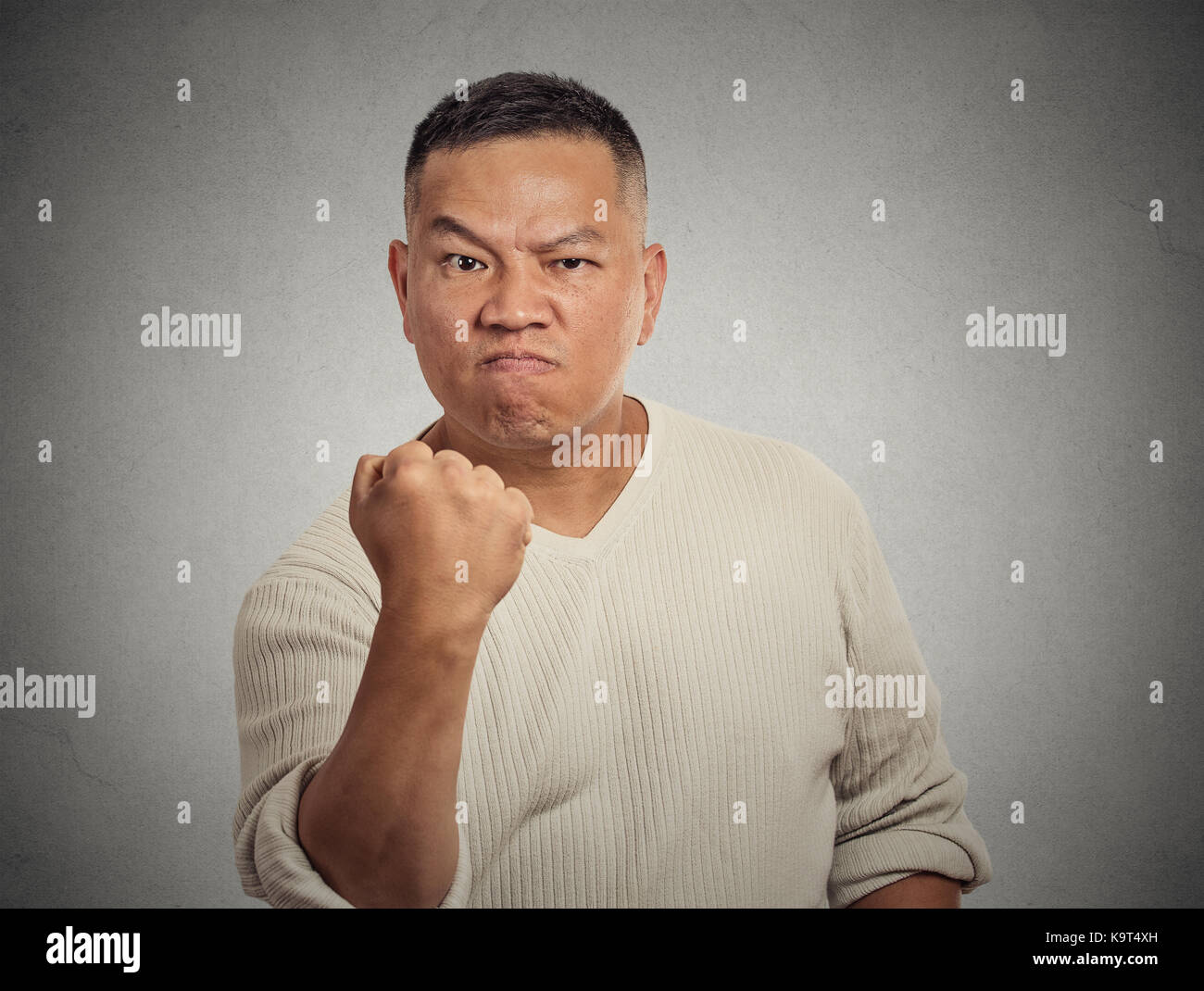 Portrait angry middle aged man fist up isolated on grey wall background ...