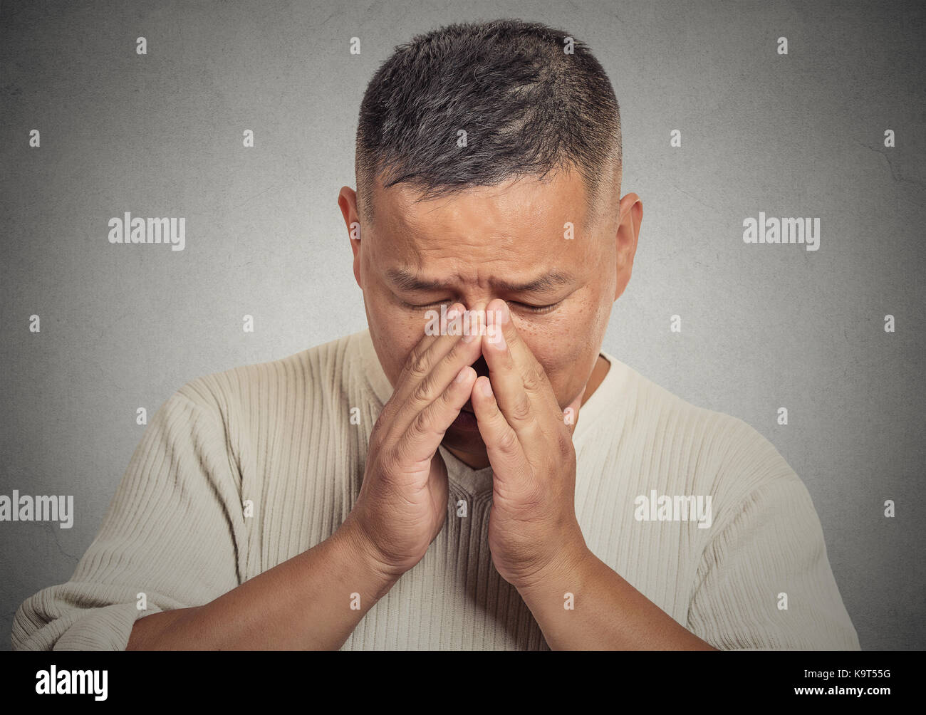 Headshot portrait of a sad young man looking down isolated on grey wall ...