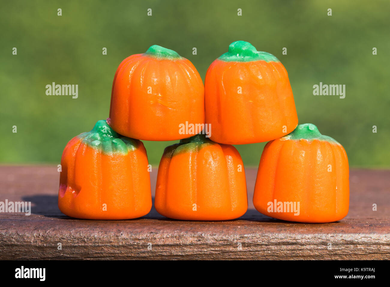 Horizontal closeup photo of candy pumpkins in a pyramid shape on wood ...