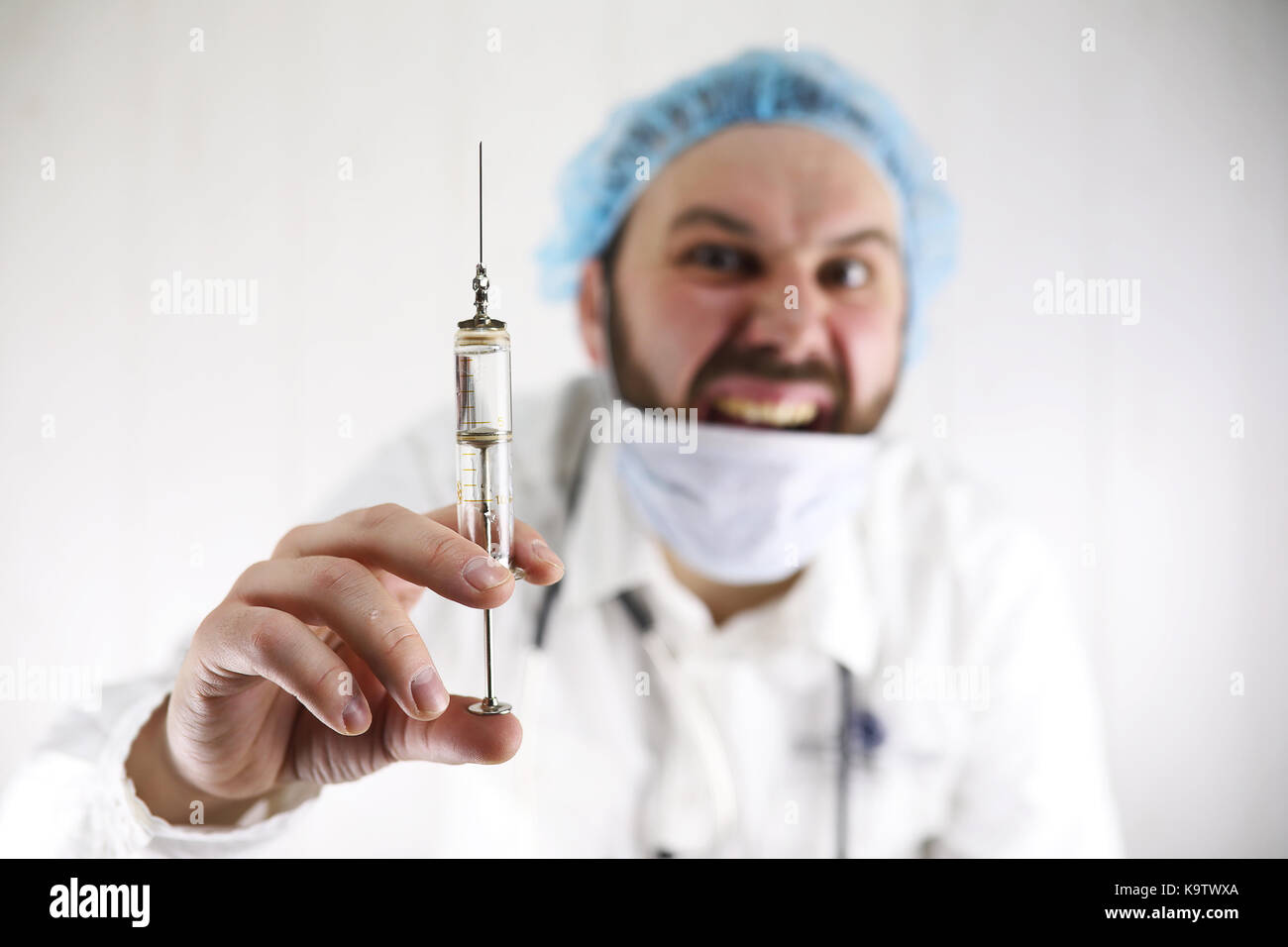Crazy bearded doctor in a white coat and old syringe Stock Photo - Alamy