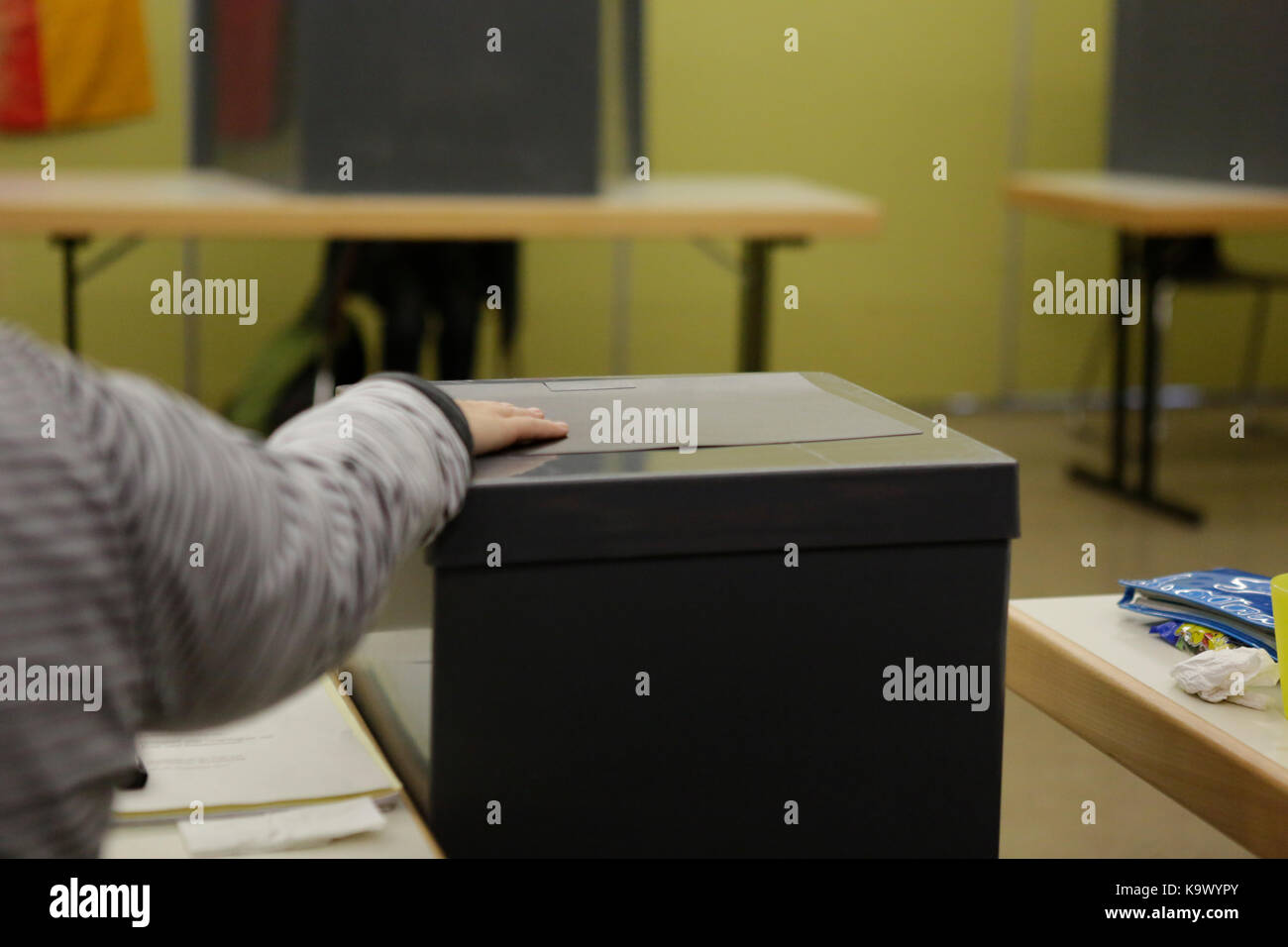 An election official has her hand on a polling box during the voting ...