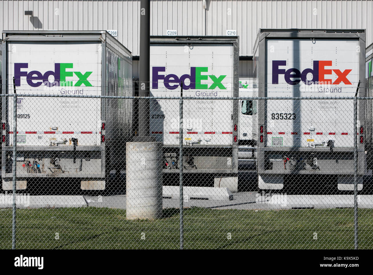 A logo sign and truck trailers outside of a FedEx Ground distribution ...