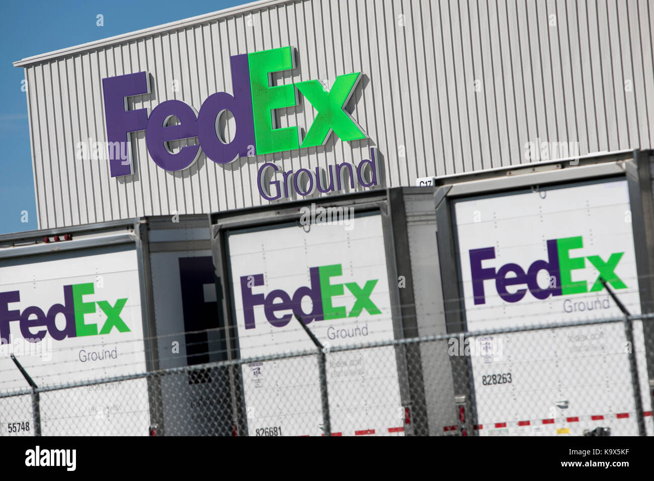 A logo sign and truck trailers outside of a FedEx Ground distribution ...