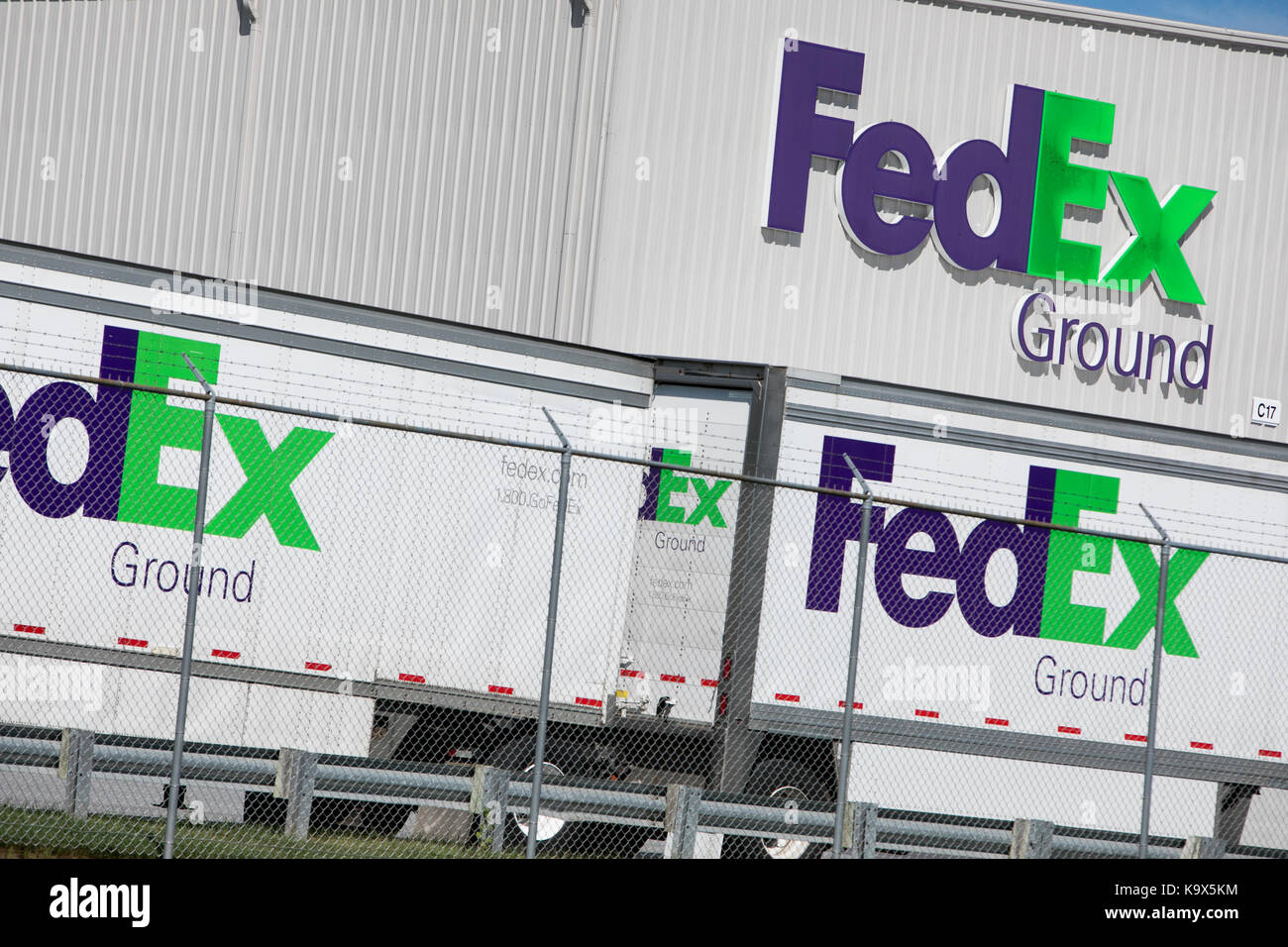 A logo sign and truck trailers outside of a FedEx Ground distribution ...
