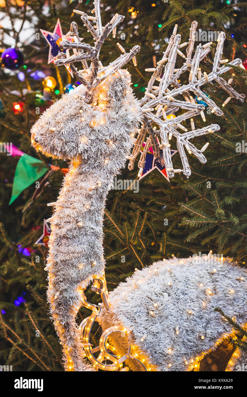 Decorated and illuminated toy reindeer under the Christmas tree on a ...