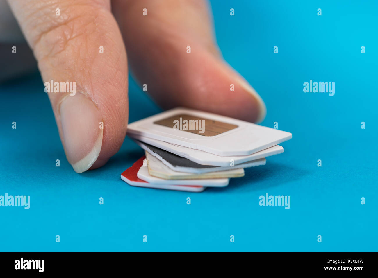 Close-up Of Hand Placing Stack Of Sim Card Over Blue Background Stock ...