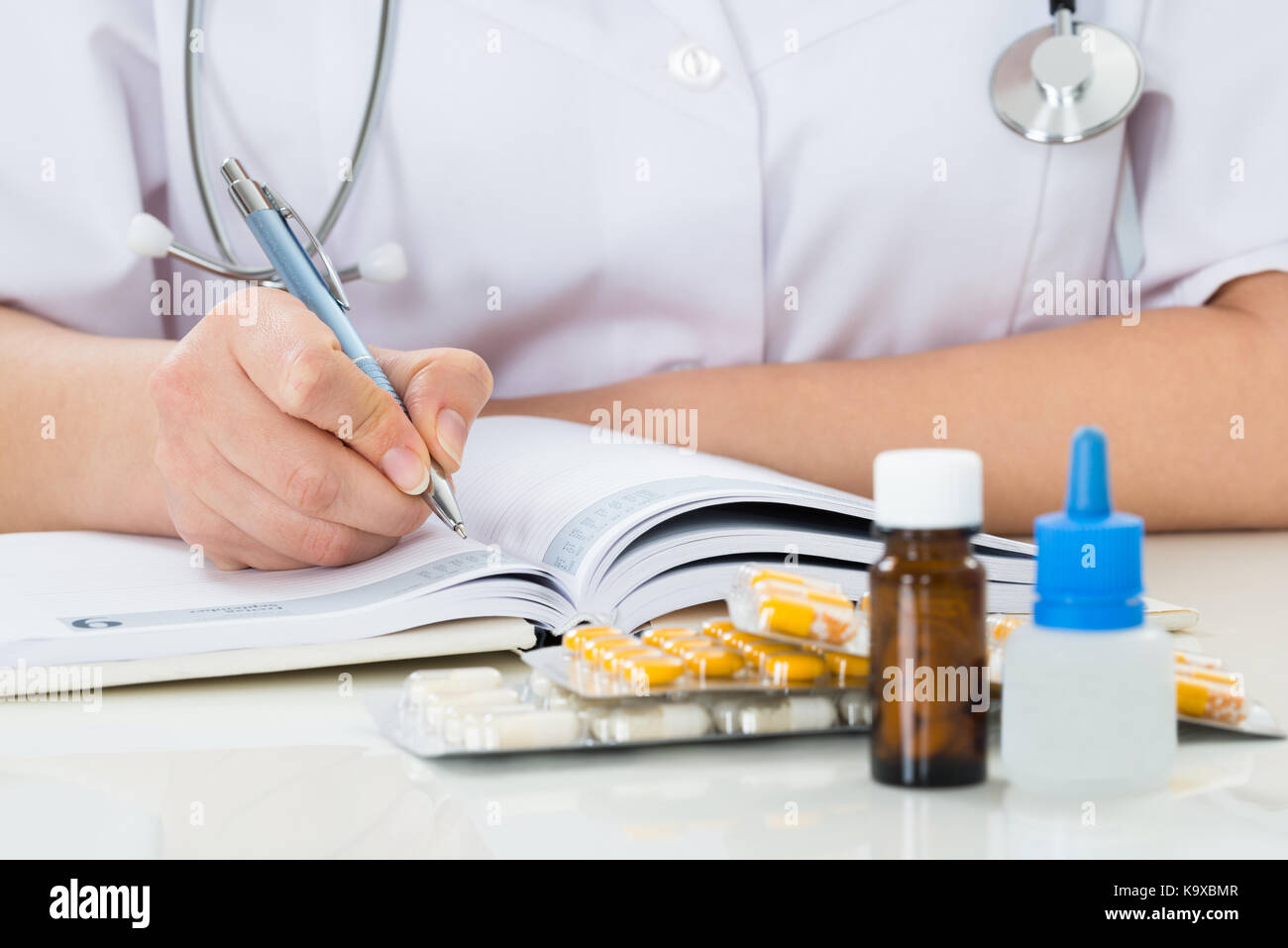 Female Doctor Writing Prescription On Clipboard At Desk In Clinic Stock ...
