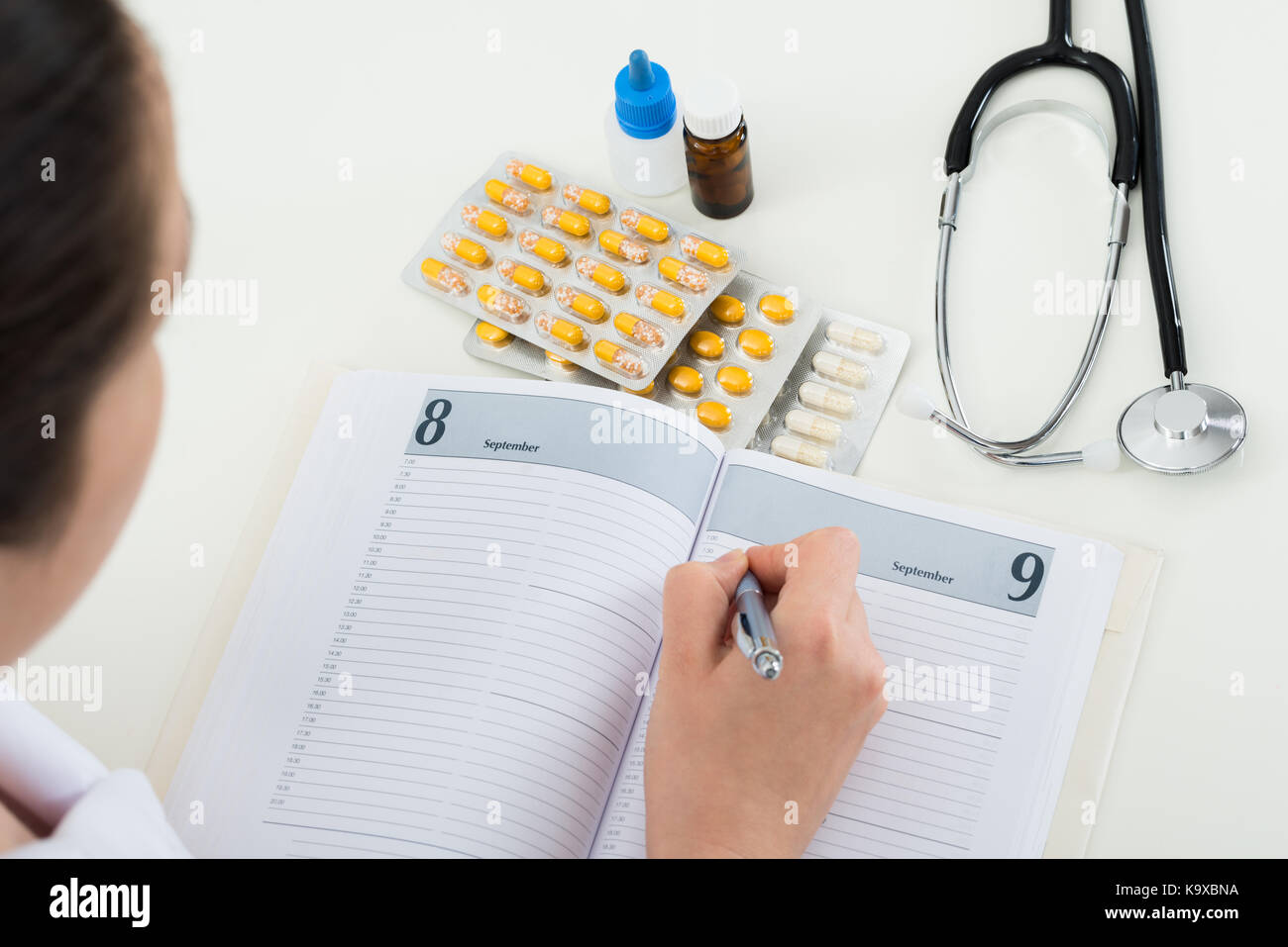 Close-up Of Female Doctor Writing In Book At Desk Stock Photo - Alamy