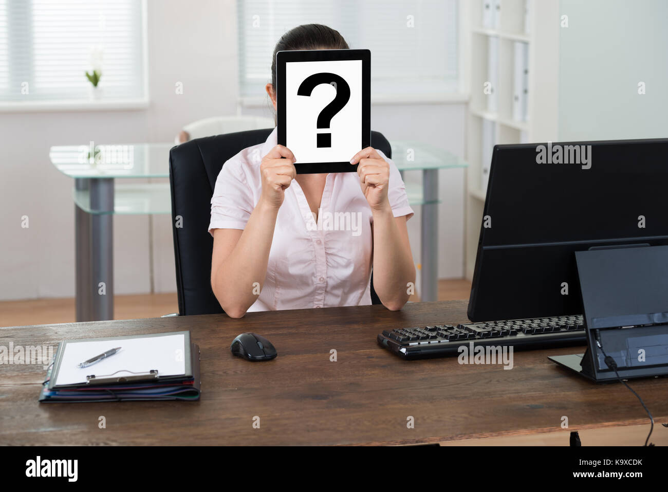 Young Businesswoman With Question Mark Sign Sitting At Desk Stock Photo ...