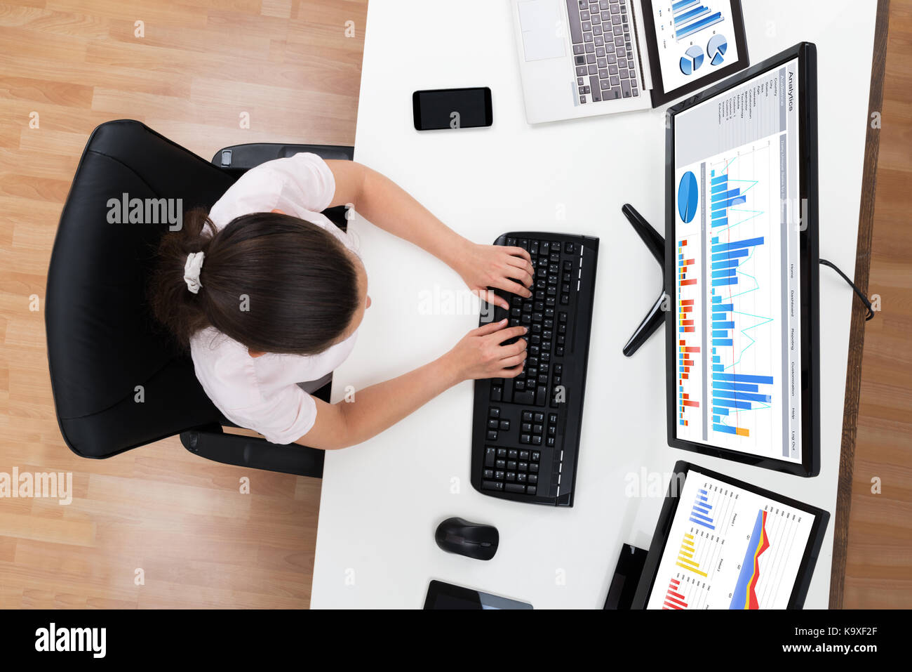 Young Businesswoman Working With Graphs On Computers At Desk Stock ...