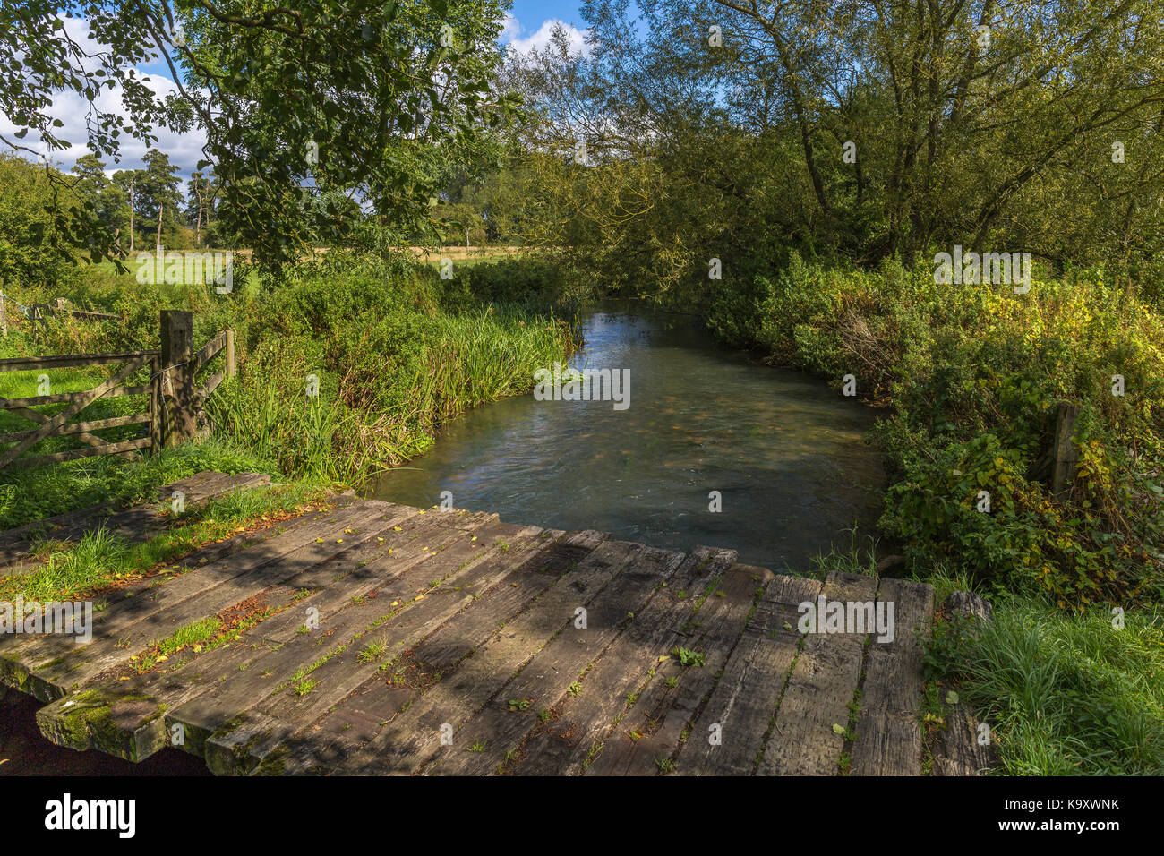 Small wooden footbridge crosses the River Windrush at Little Barrington ...